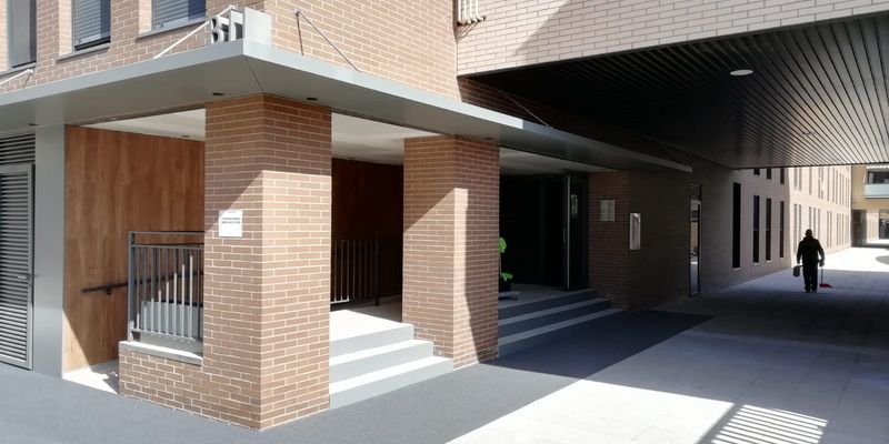 Fachada edificio residencial: voladizo metálico y puertas de contadores